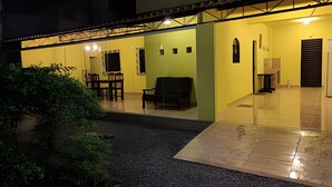 Um edifício moderno com fachada de vidro, área de pátio com assentos e entrada visível.