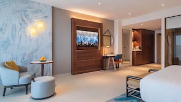 Quarto de hotel moderno com cama, área de estar com mesa pequena, espelho grande e parede com padrão de luz.