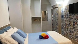 Quarto moderno com cama, luminária pendente azul e parede revestida com padrão geométrico.