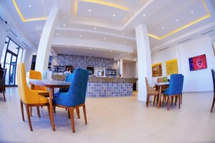 Um saguão de hotel moderno com área de bar, espaços para sentar e obras de arte nas paredes.