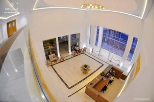 Um hall amplo com balcão de recepção, área de estar e grandes janelas.