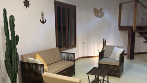 Uma sala de estar com móveis de vime, um cacto em vaso e arte decorativa na parede.