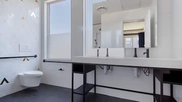 Uma casa de banho moderna com lavatório branco, espelho e sanita.