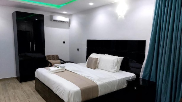 Quarto de hotel moderno com uma cama grande, um guarda-roupa e uma televisão de tela plana.