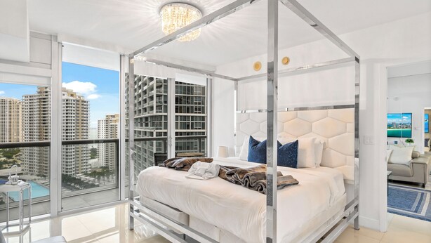 Quarto moderno com cama de dossel de vidro, vista para a cidade e varanda com piscina.