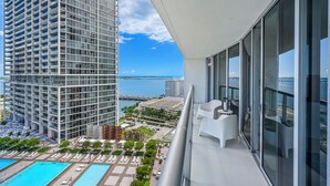 Um edifício alto com varanda, vista para uma piscina e um porto.