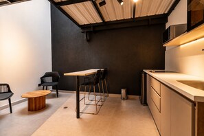 Uma cozinha moderna com uma mesa e cadeiras de madeira, uma cadeira preta e uma pia de aço inoxidável.