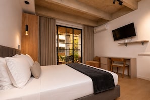 Quarto de hotel moderno com uma cama grande, escrivaninha, televisão e janela com cortinas.