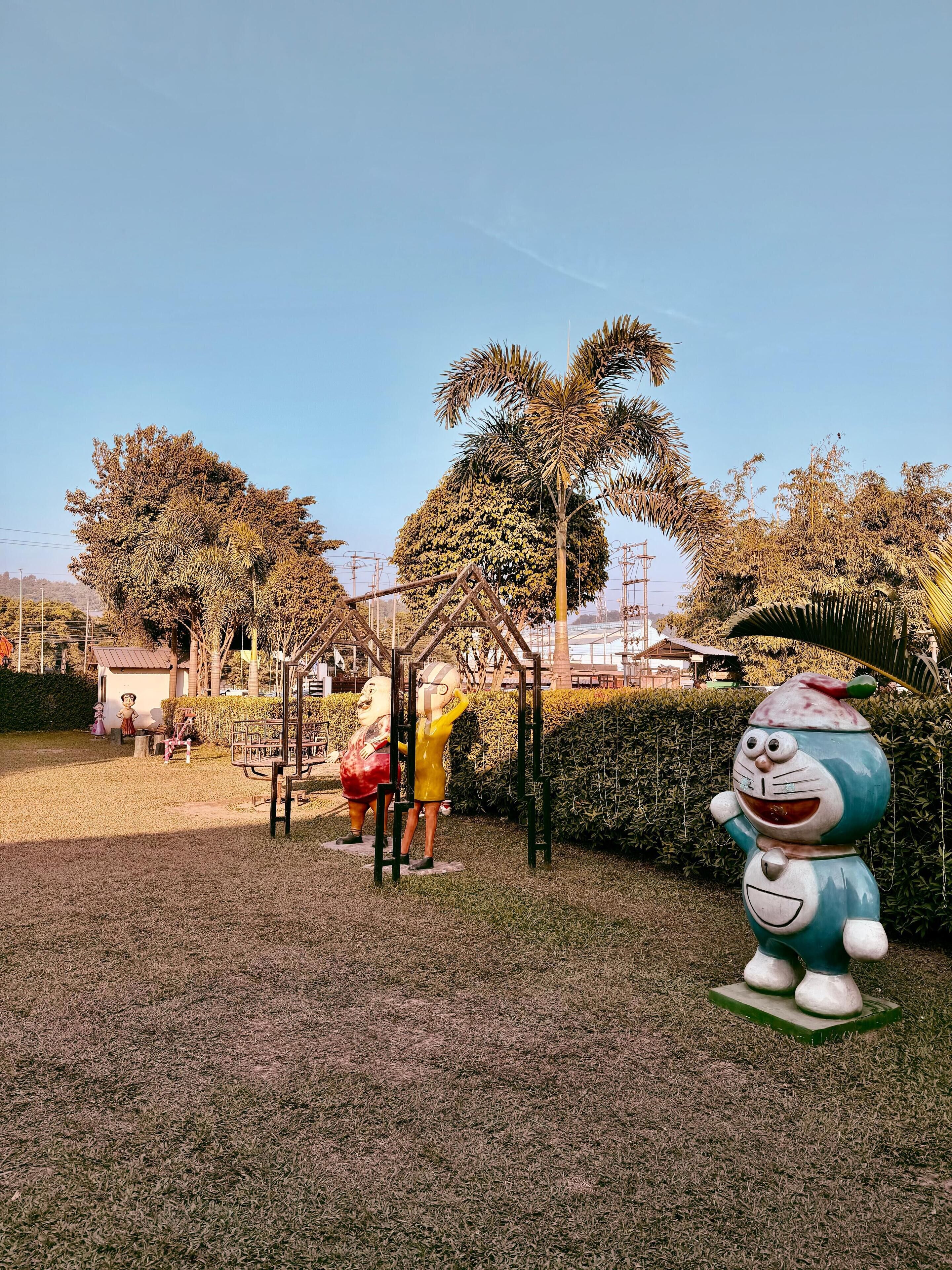Um parquinho com baloiços e uma grande estátua de personagem de desenho animado.