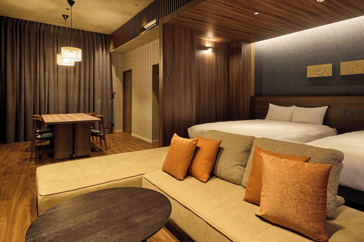 Quarto de hotel com uma cama grande, um sofá, uma mesa pequena e uma escrivaninha.
