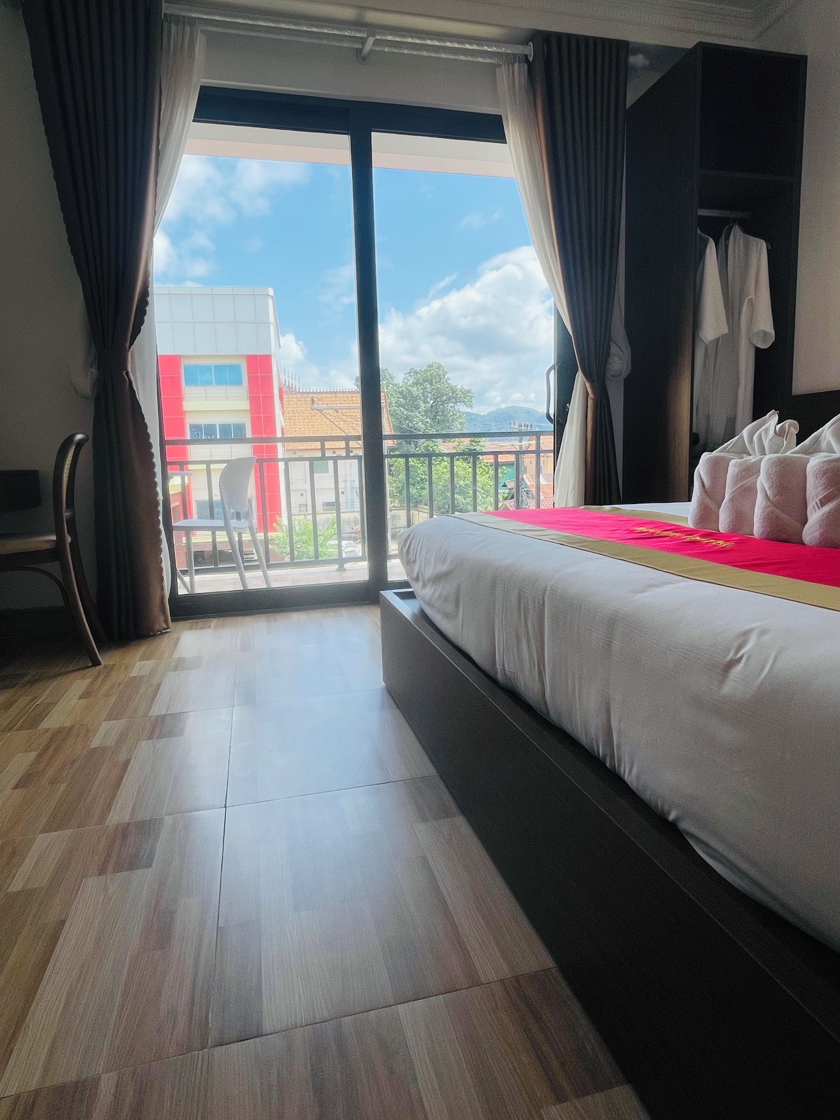 Quarto de hotel com cama, cadeira, guarda-roupa e vista para o exterior.
