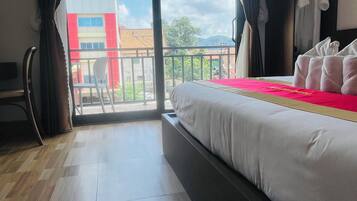 Quarto de hotel com cama, cadeira, guarda-roupa e vista para o exterior.