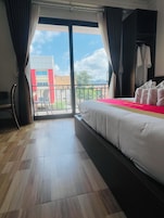 Quarto de hotel com cama, cadeira, guarda-roupa e vista para o exterior.