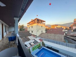 Terraço no telhado com piscina, área de refeições e vista para edifícios próximos.