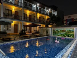 Piscina de hotel com espreguiçadeiras e guarda-sóis, um flutuador de cisne e um mural de paisagem.
