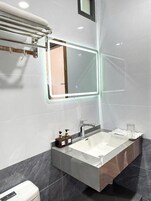 Um banheiro moderno com um espelho retangular grande, um lavatório embutido e um porta-toalhas.
