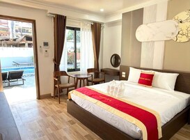 Quarto de hotel com uma cama, uma escrivaninha e vista para o mar.