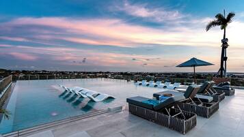 Piscina no terraço com espreguiçadeiras e uma palmeira.