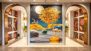 Um corredor com um mural representando uma árvore, veados e formas abstratas.