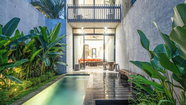 Uma casa moderna com piscina, área de estar externa e vegetação exuberante.