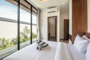 Quarto de hotel com uma cama grande, vista para palmeiras e ar condicionado.