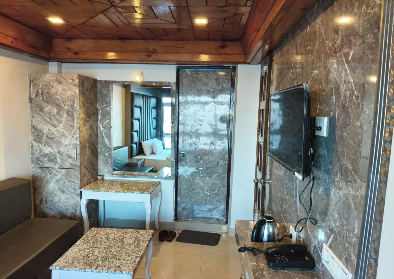 Casa de banho moderna com bancada de granito, pia, espelho, área de duche e televisão montada na parede.