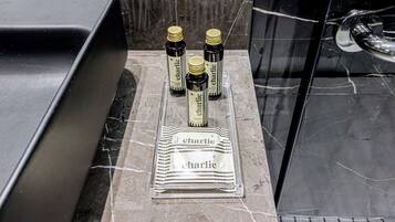 Uma bancada de mármore com três frascos de colônia Charlie e um frasco maior de spray corporal Charlie.