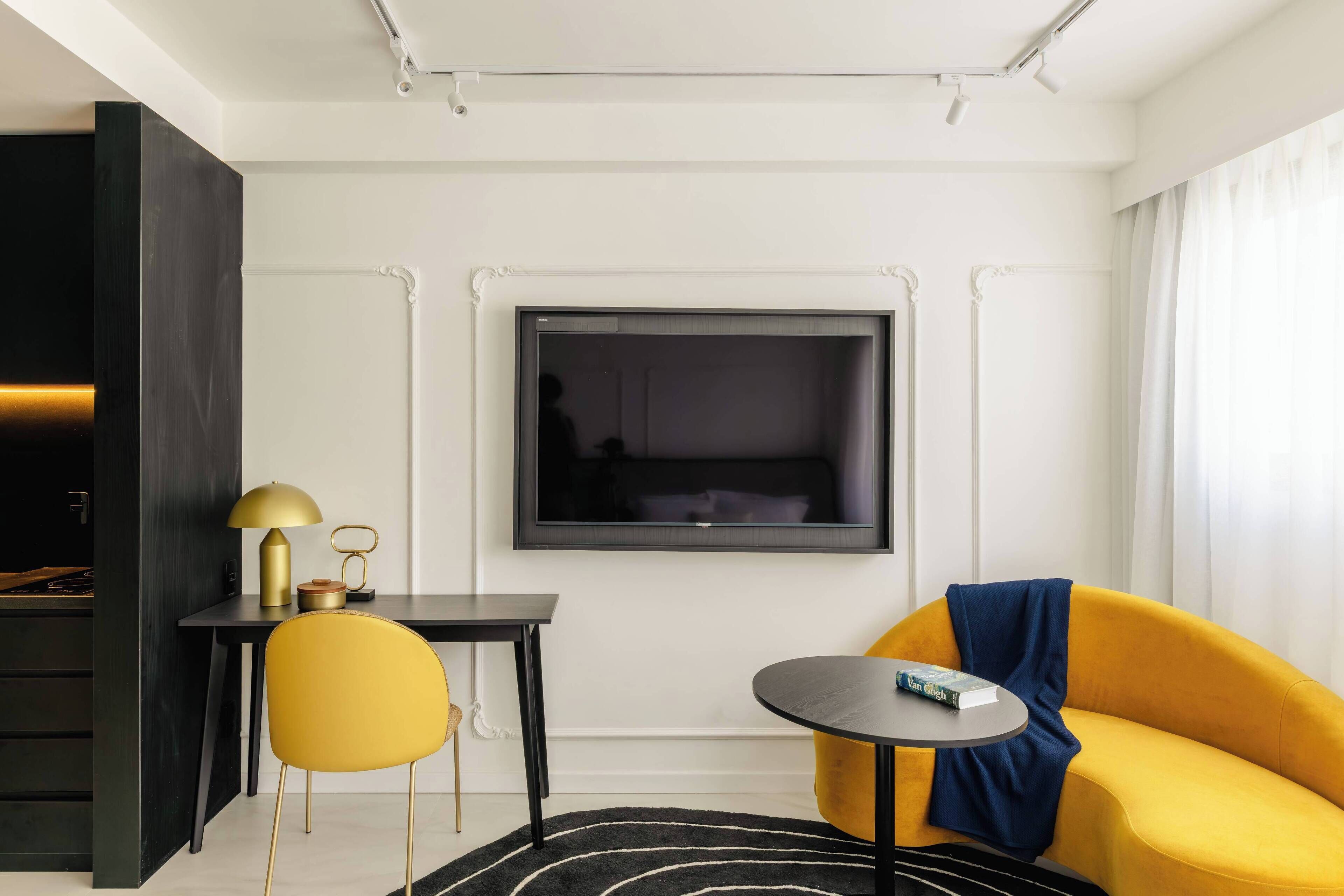 Quarto moderno com escrivaninha preta, cadeira amarela e sofá amarelo.