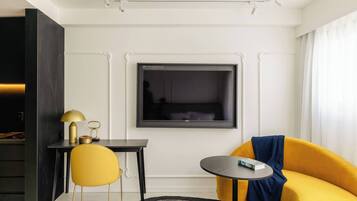 Quarto moderno com escrivaninha preta, cadeira amarela e sofá amarelo.