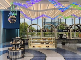 Um interior moderno com uma vitrine de vidro exibindo doces, uma máquina de café e uma seleção de bebidas engarrafadas.