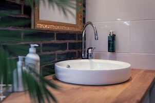 Casa de banho com lavatório branco, torneira moderna e dispensador de sabonete líquido no balcão.