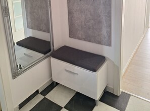 Casa de banho com toucador branco, espelho grande e parede cinzenta.