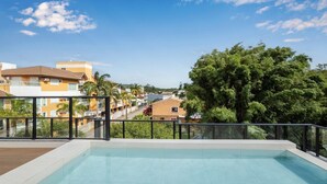 Piscina no terraço com vista clara para edifícios e árvores ao redor.