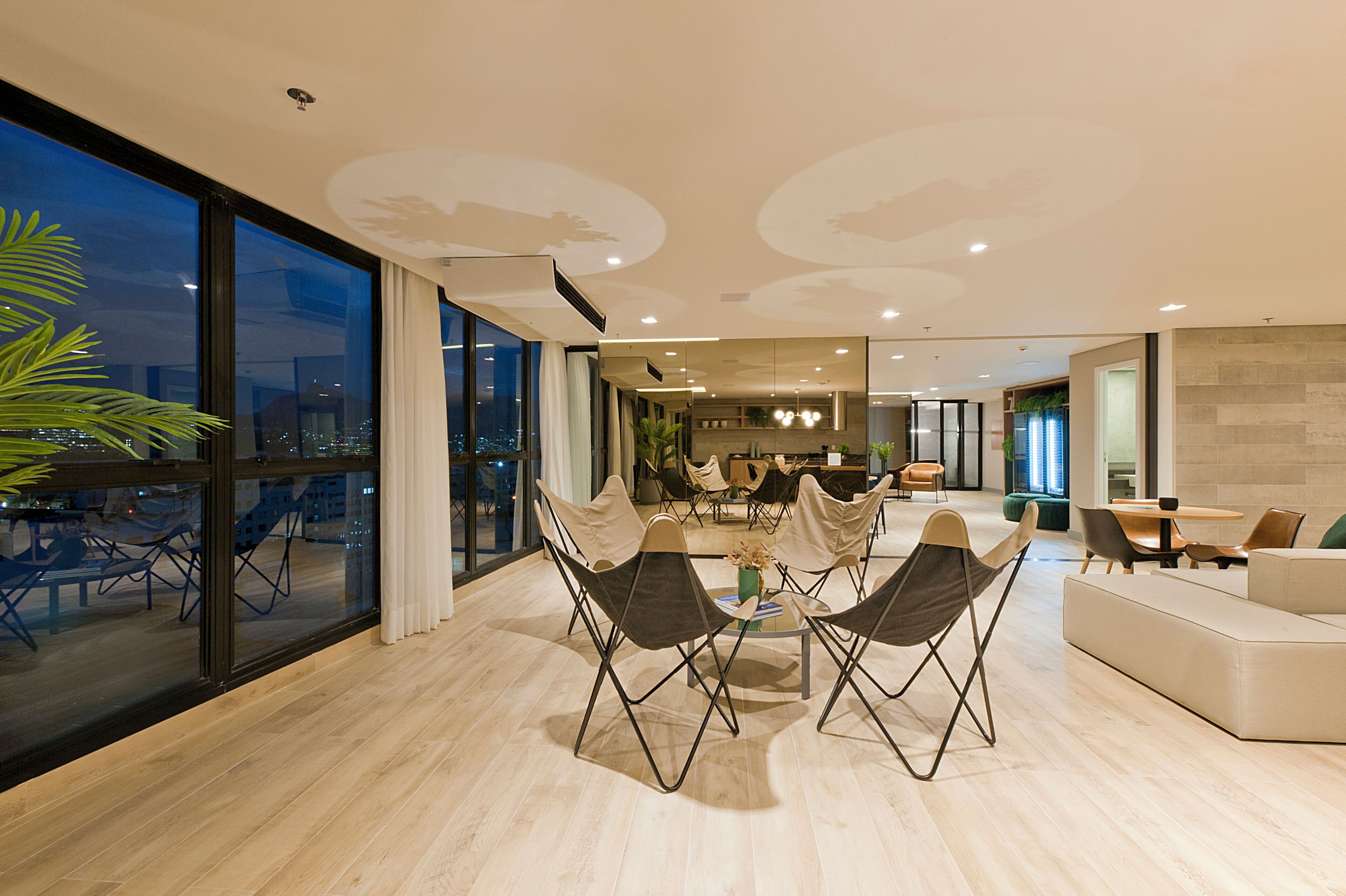 Uma área de jantar moderna com teto alto, grandes janelas e vista para a cidade.