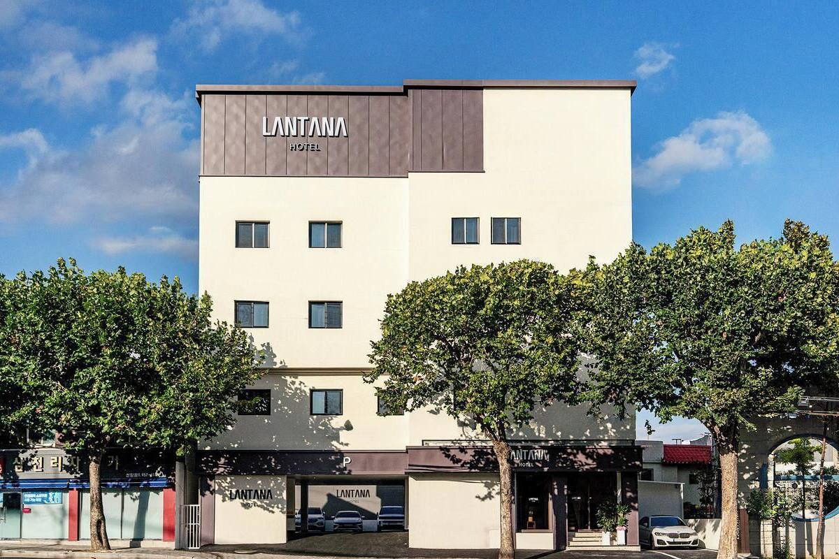Um hotel moderno com fachada plana, várias janelas e uma placa com a inscrição 'LANTANA HOTEL'.