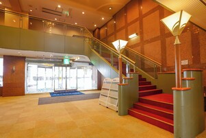 Um hall amplo com escada, área de recepção e vista para o exterior.
