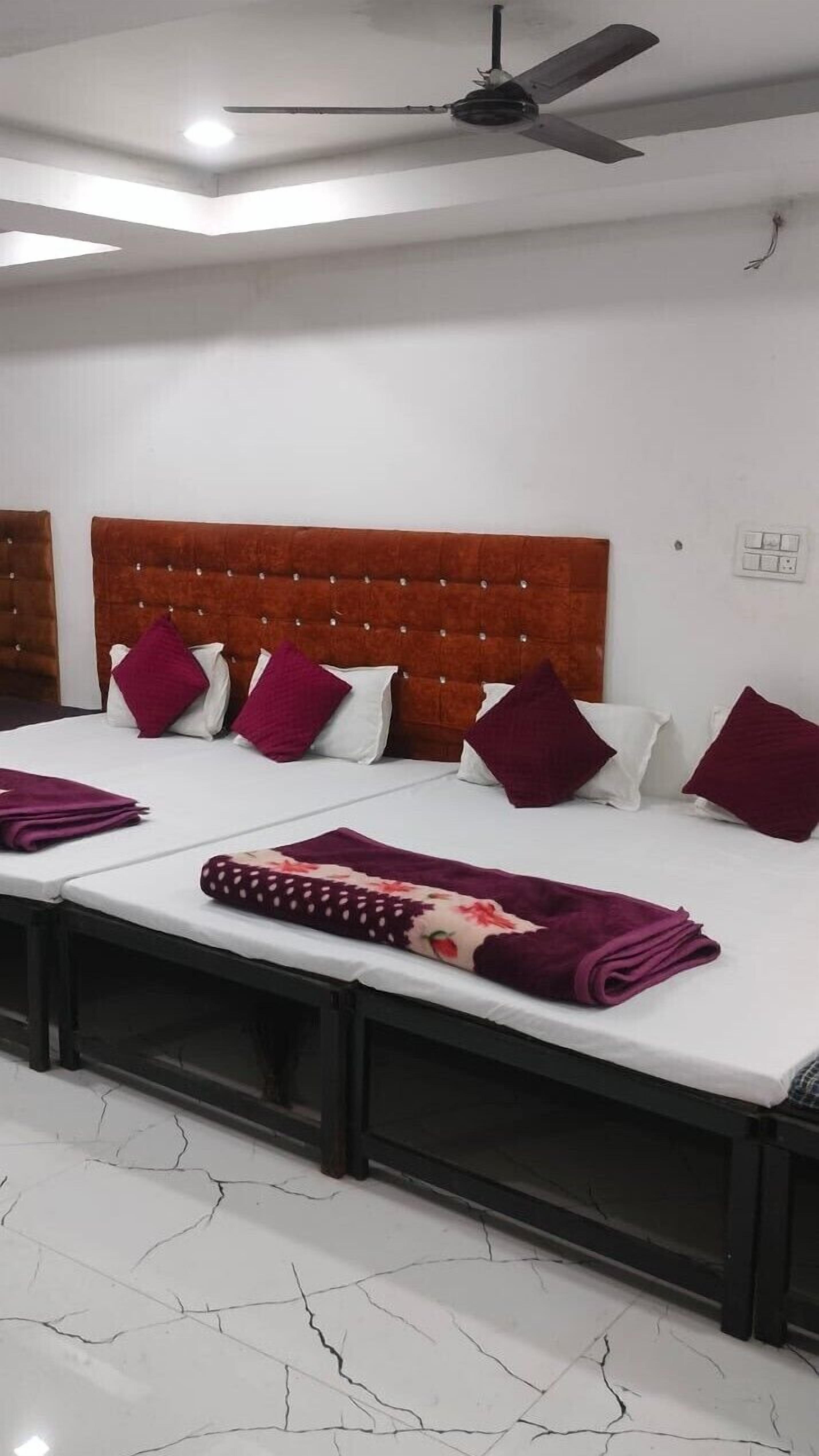 Quarto de hotel com uma cama grande, cabeceira de madeira e ventoinha de teto.
