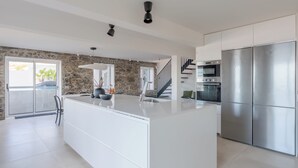 Uma cozinha moderna com uma ilha grande, eletrodomésticos de aço inoxidável e uma parede com detalhes em pedra.