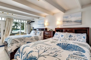 Quarto com duas camas, mesa de cabeceira, cômoda e um quadro na parede.
