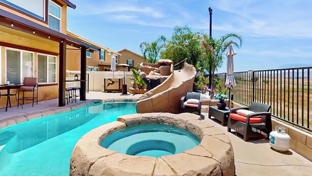 Um quintal com piscina, banheira de hidromassagem e móveis de exterior.