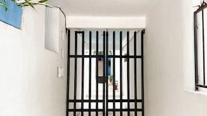 Um corredor estreito com um portão de metal preto que dá para uma escada.