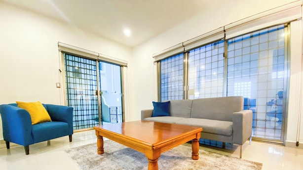 Uma sala de estar com um sofá azul, um sofá cinza e uma mesa de centro de madeira.