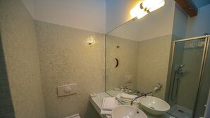 Casa de banho com duas pias, sanita, chuveiro e espelho.
