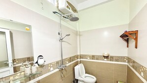 Um banheiro com pia, vaso sanitário, chuveiro e espelho.