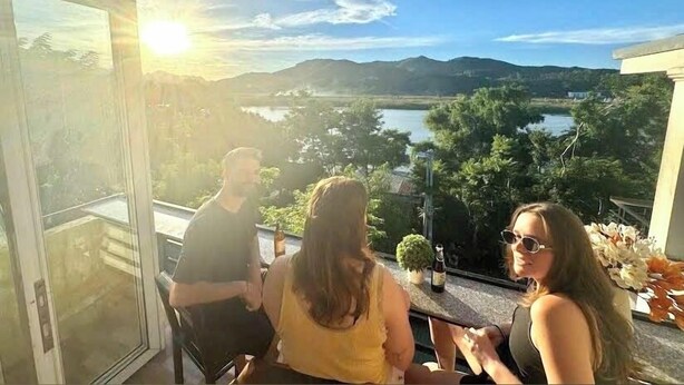 Uma varanda com vista para um lago e colinas.