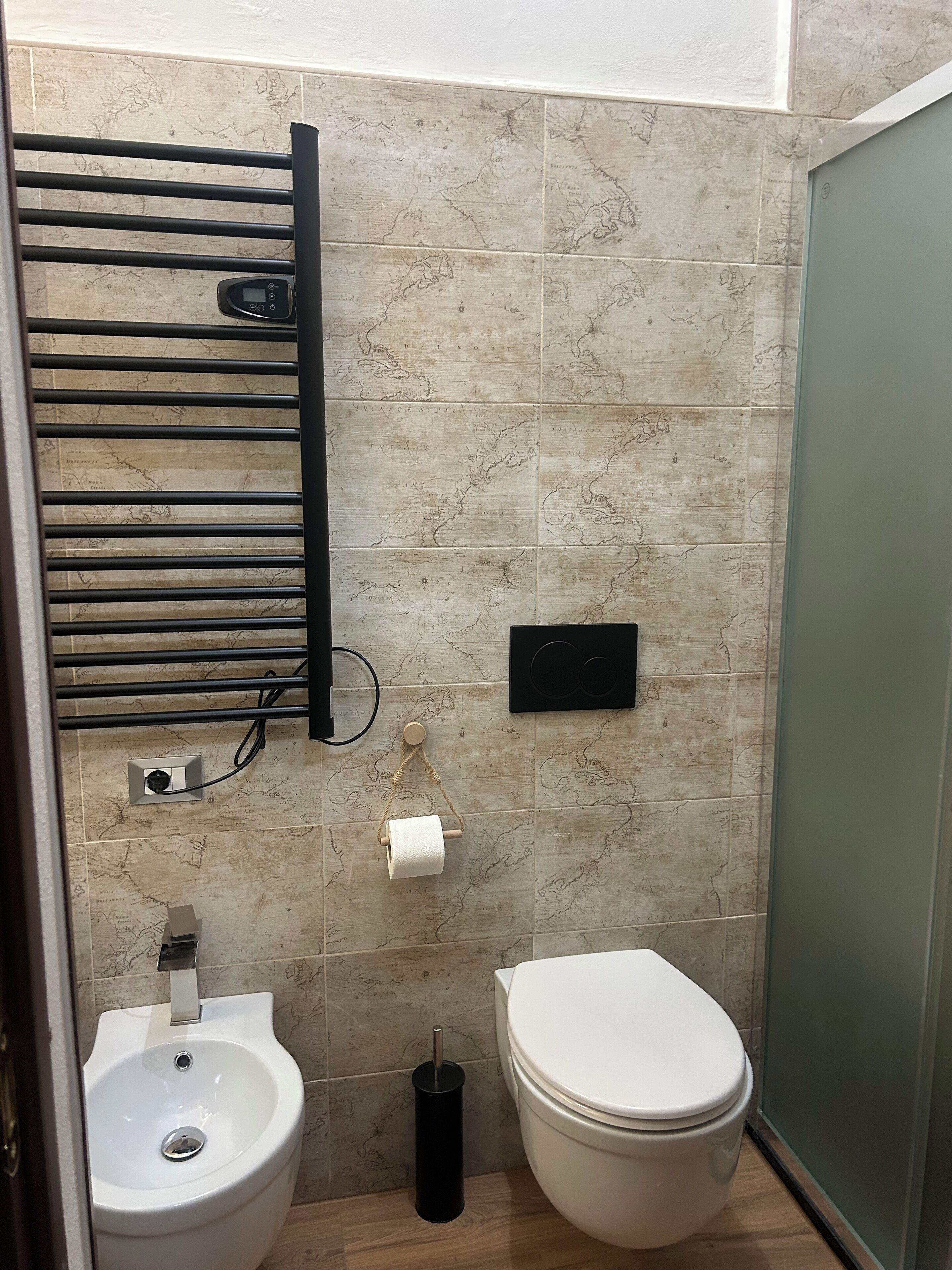 Casa de banho com bidé, sanita, porta-toalhas e painel de comando fixado na parede.