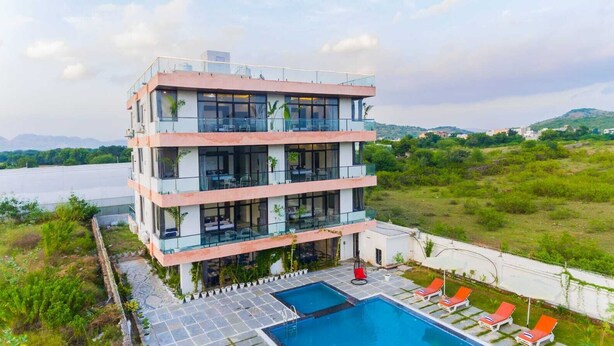 Um edifício com vários andares, piscina e área externa com mesas.