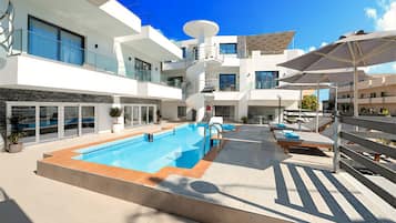 Um hotel moderno com piscina central, área de estar externa e design em vários níveis.
