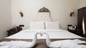 Quarto de hotel com cama grande, duas mesas de cabeceira, luminária na parede e cabeceira decorativa.