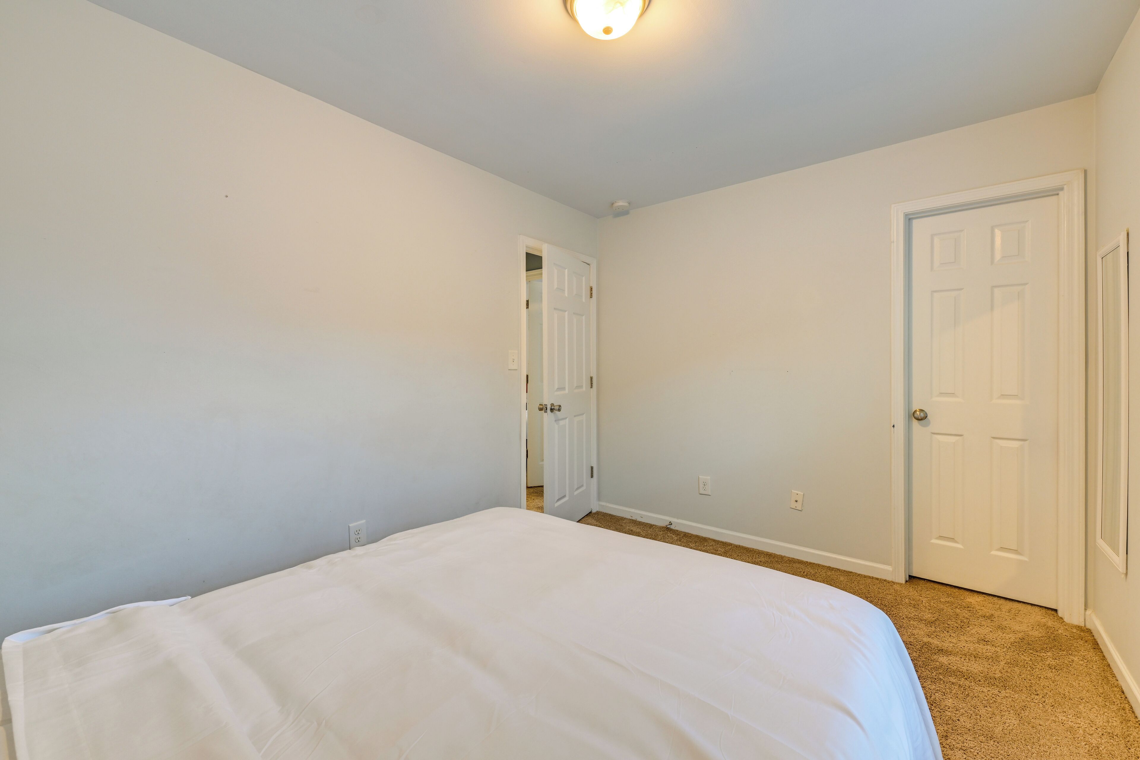 Quarto com cama, porta e luminária.